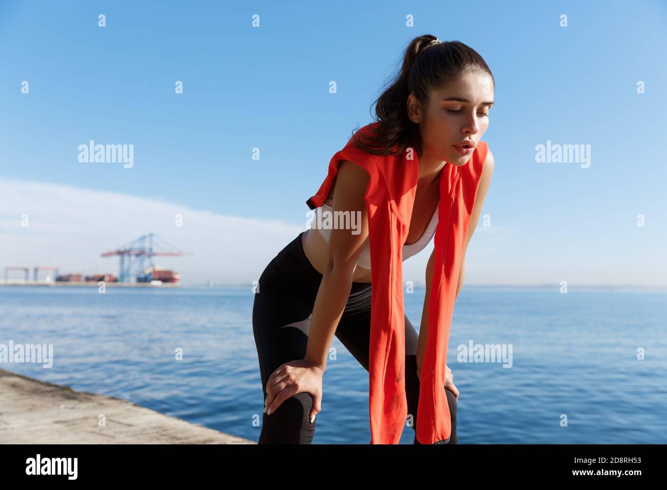 Outdoor shot of tired fitness woman panting and taking a breath after ...