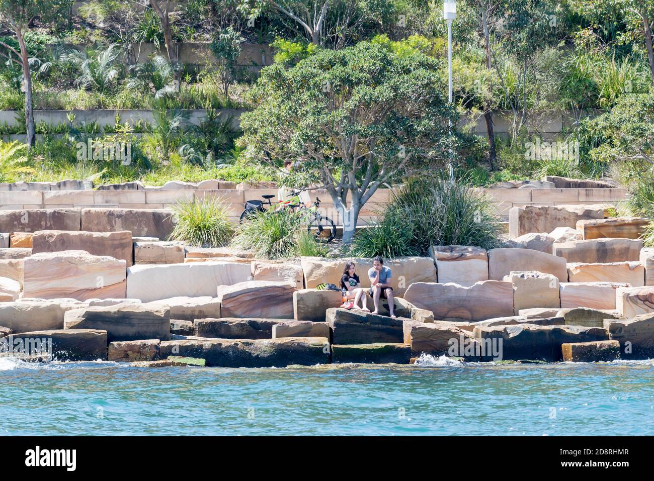 A young couple sit on the giant sandstone blocks at Barangaroo Reserve ...
