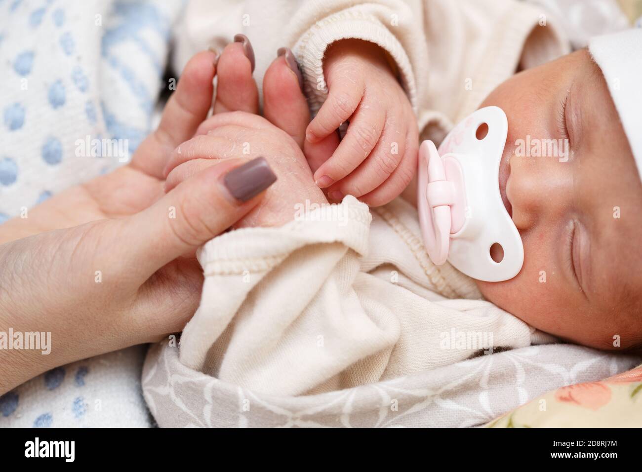small fingers, hands of a newborn baby close-up. baby has pacifier in ...