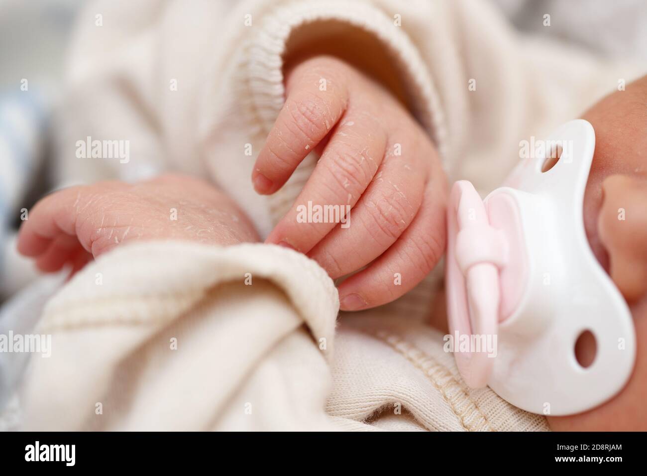 small fingers, hands of a newborn baby close-up. baby has pacifier in ...