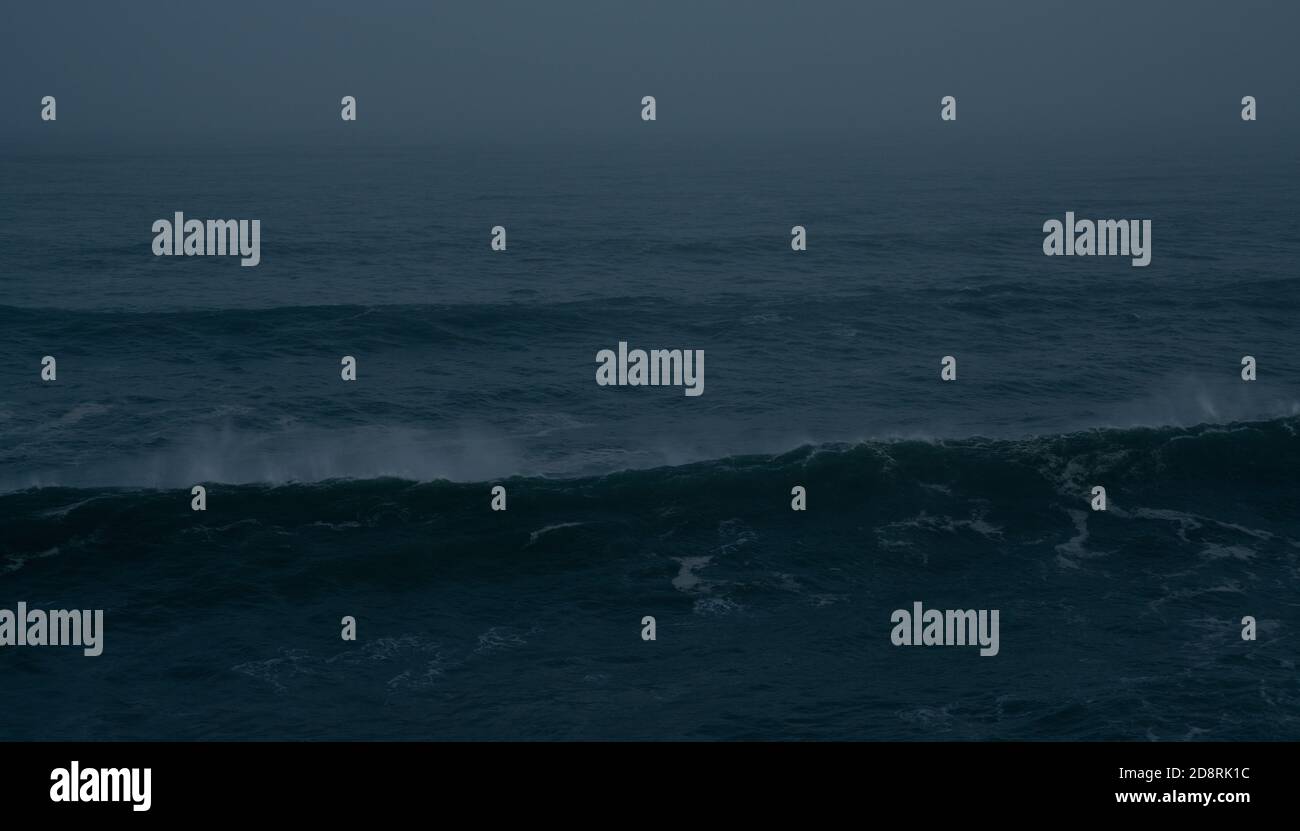 Detail view of large waves breaking in the open ocean at night during a ...