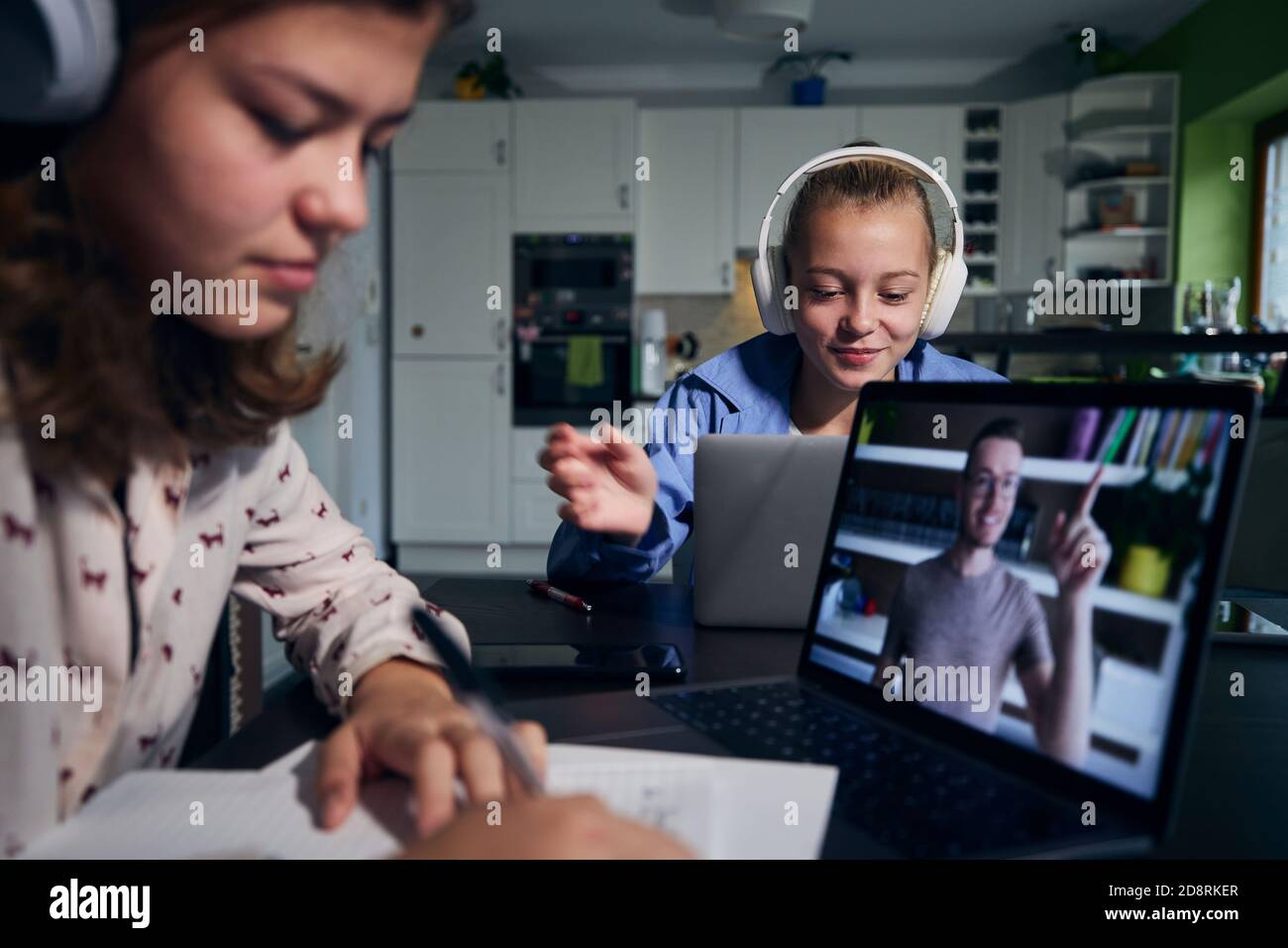 Online school lesson. Two girls learning via internet with laptops at ...