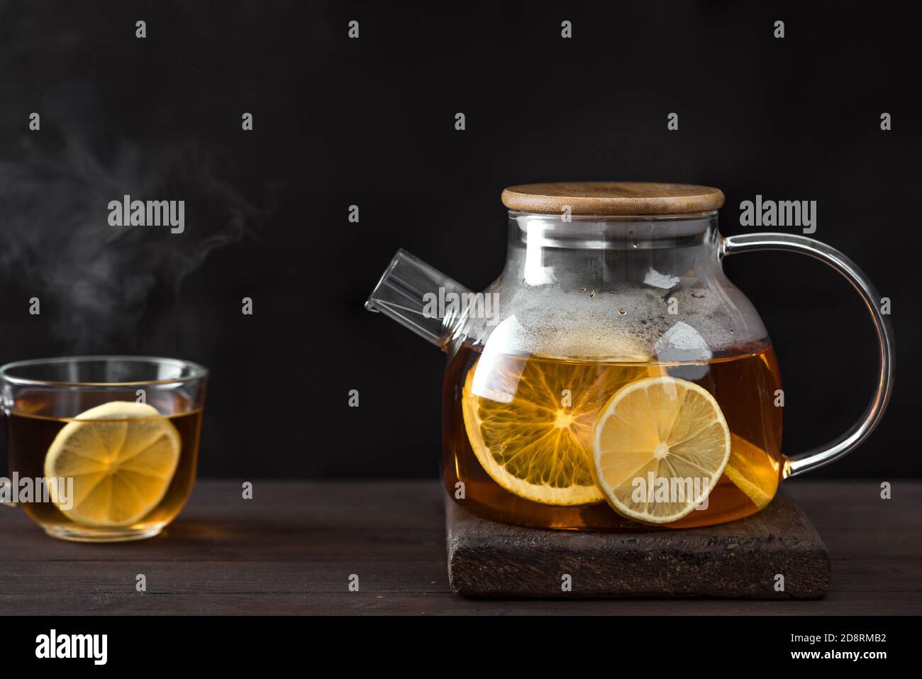 Citrus tea with lemon, oranges in transparent glass teapot on dark ...