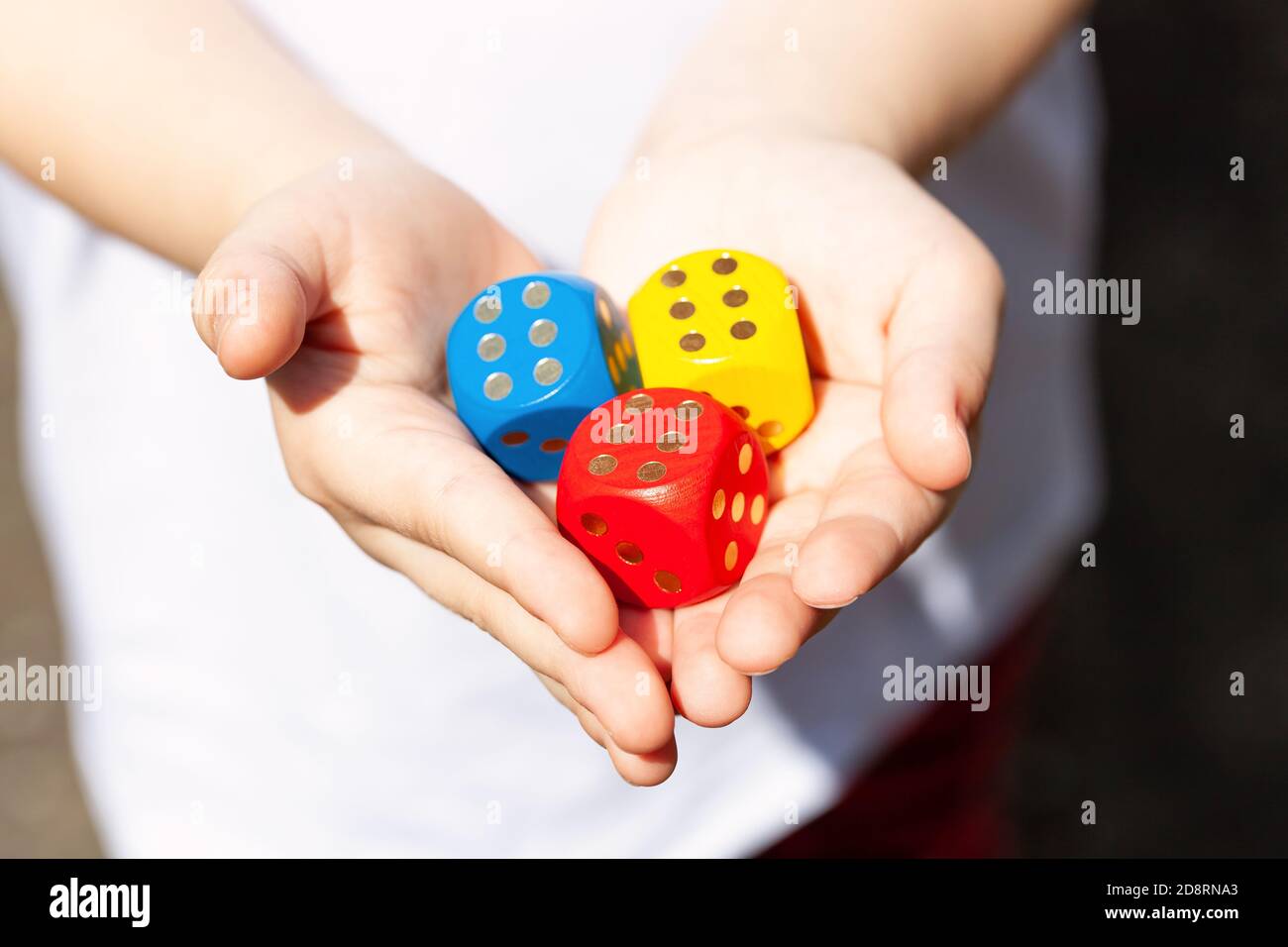 Little child holding three colorful wooden dice showing six in her ...