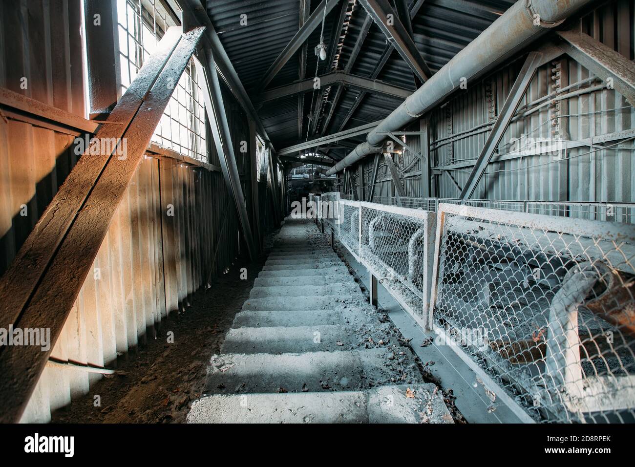 Abandoned cement and concrete factory. Old rusty conveyor in corridor ...