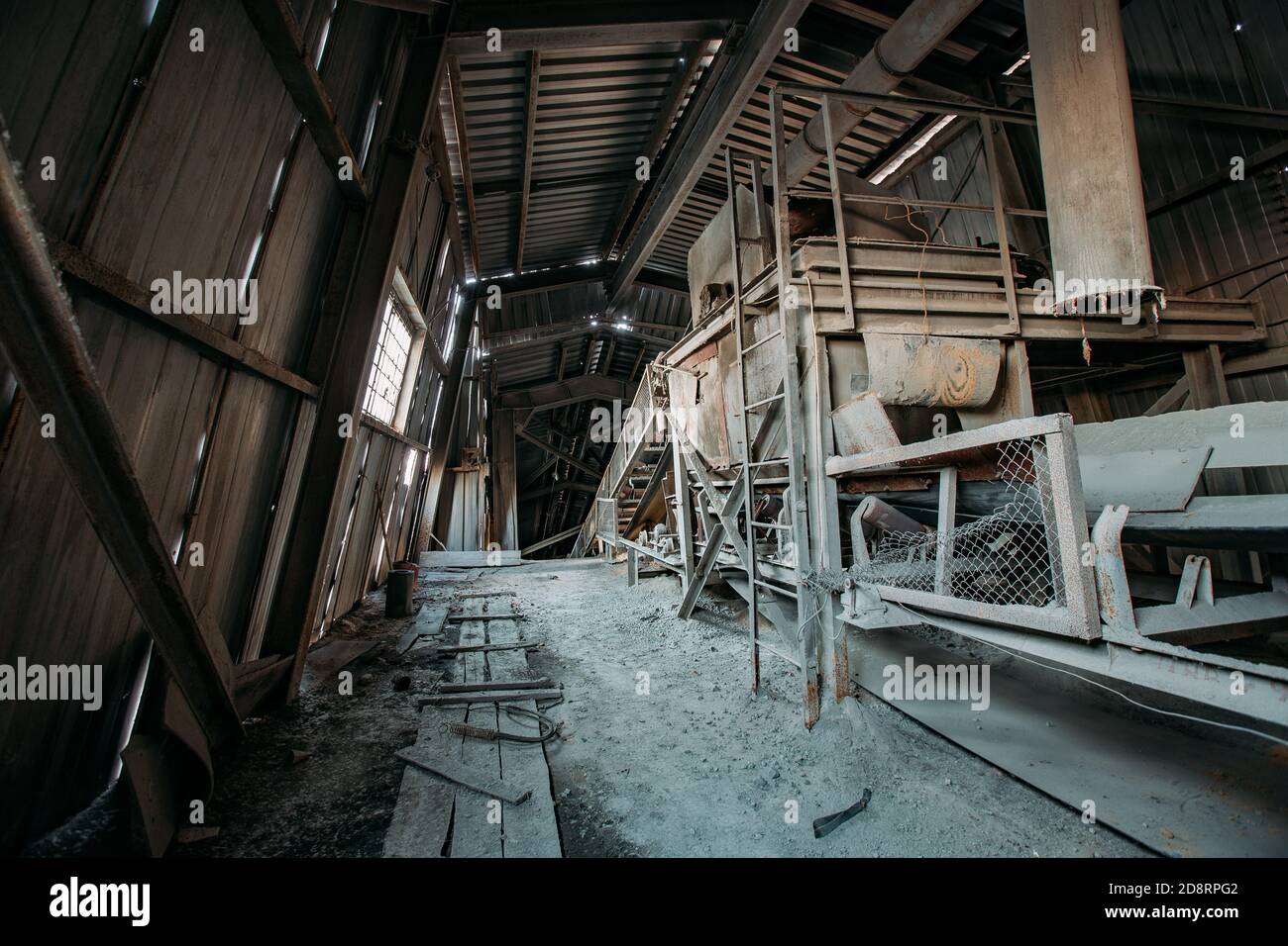 Abandoned cement and concrete factory. Old rusty conveyor in corridor ...