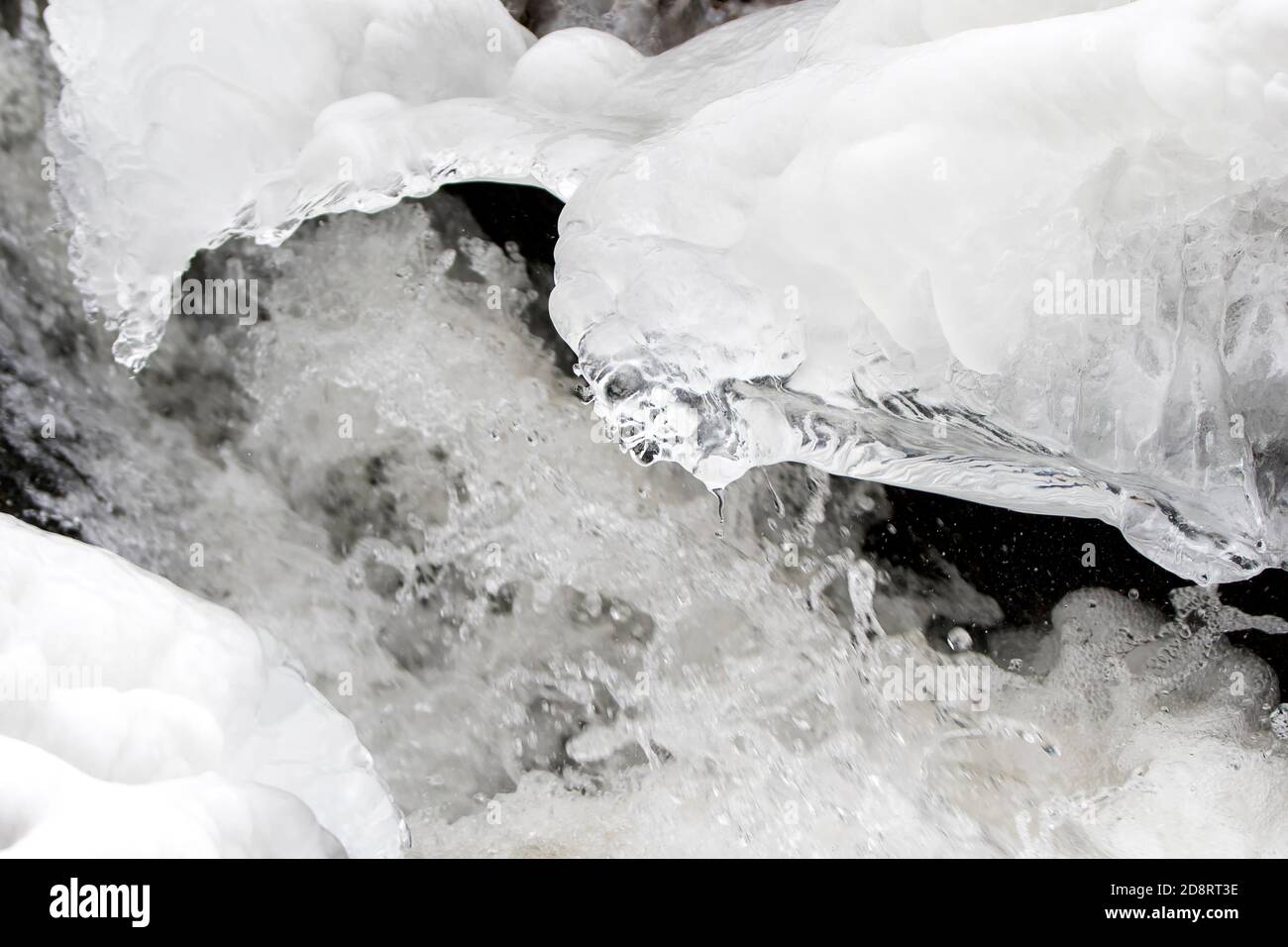 Water flowing in a small frozen waterfall. The water is rapidly flowing ...