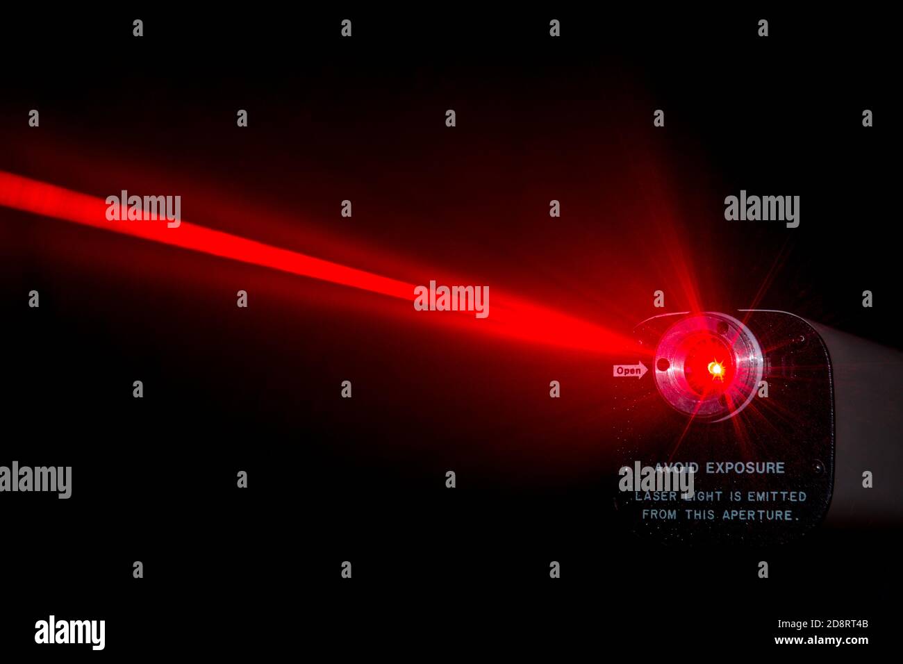 Red laser beam from a lab laser. Warning notice on front. Black ...