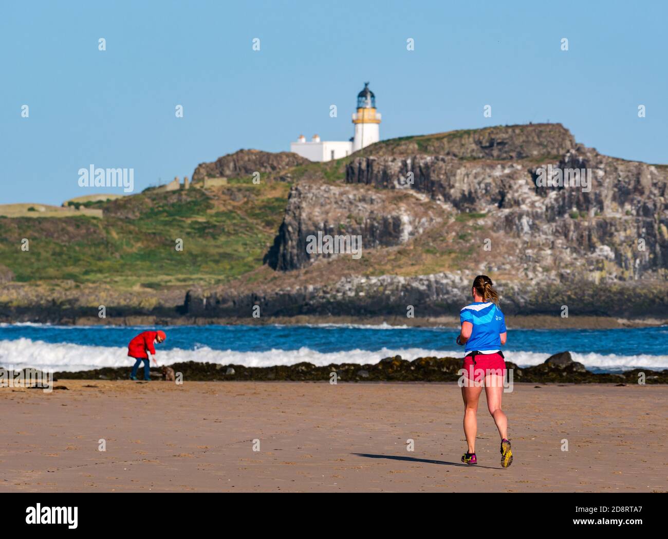 Female runner, Yellowcraig beach with Fidra Island & lighthouse, East ...