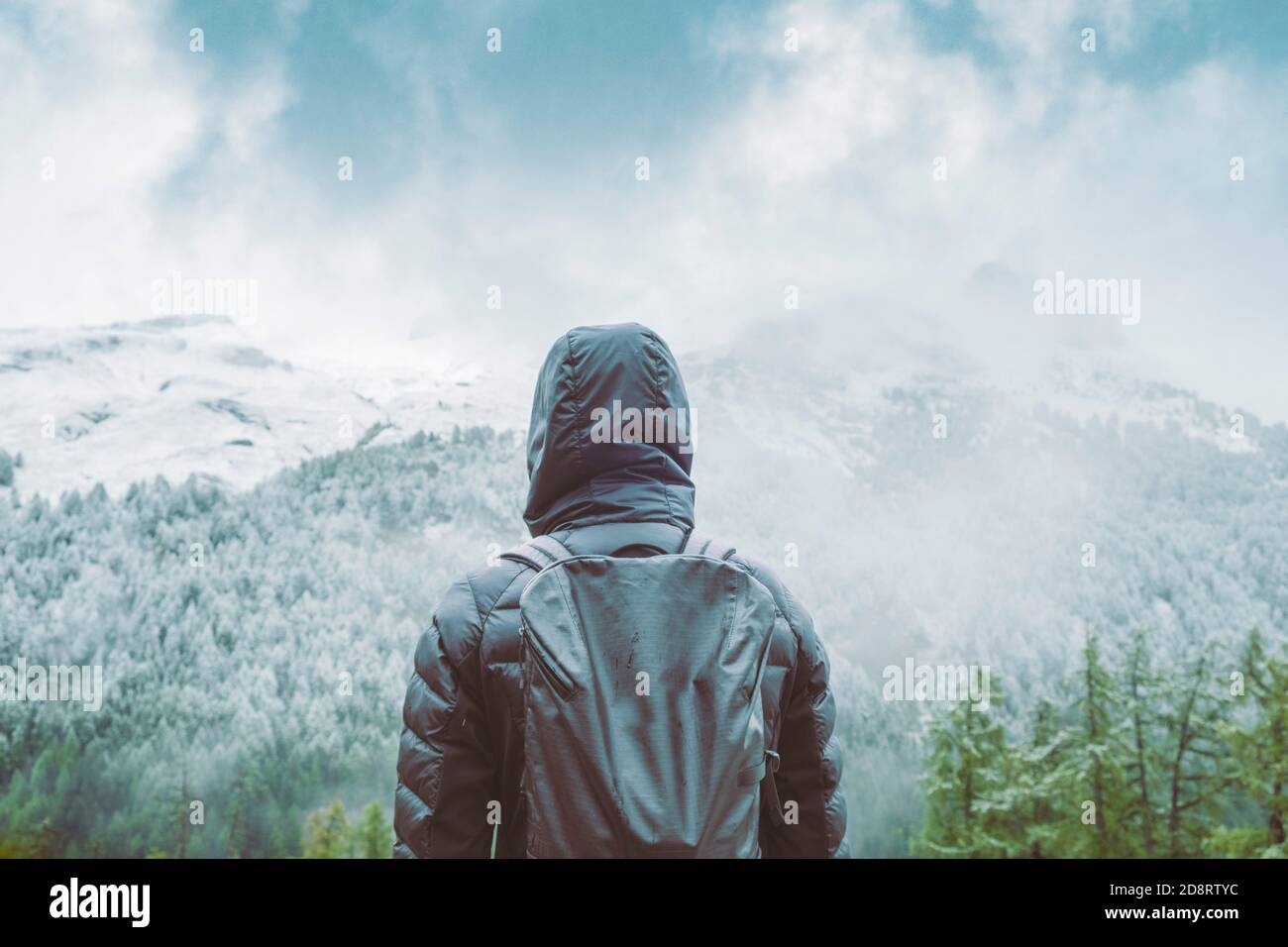 Rear view of person, standing in front of a slight snow capped mountain ...