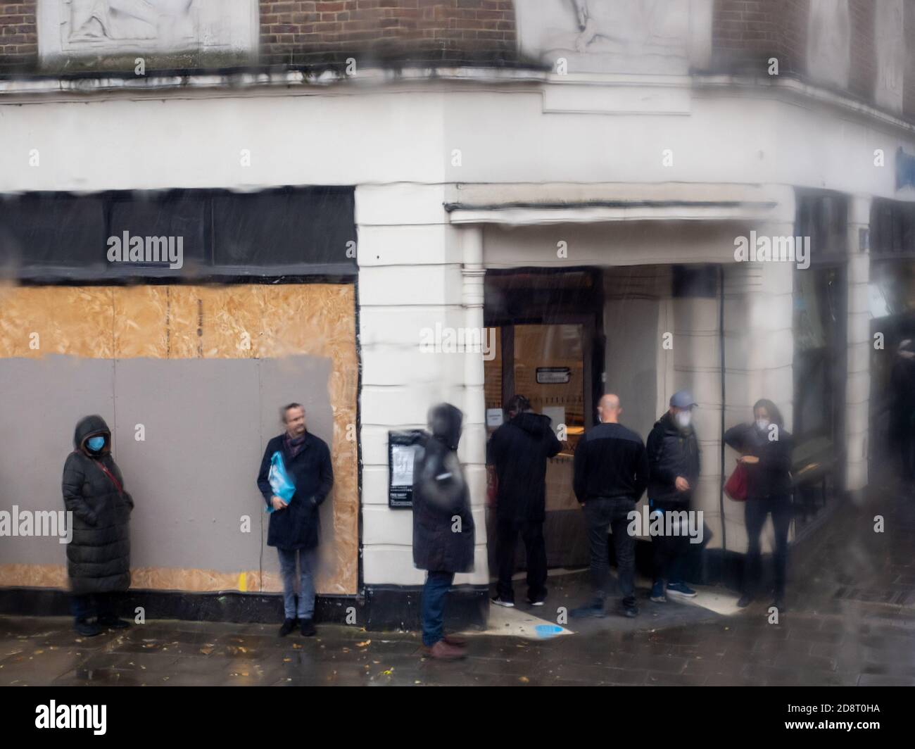 Customers at Barclays bank wearing face masks wueue in the rain Stock ...