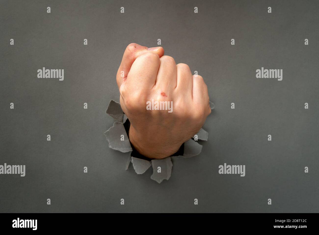 Male fist breaking through a grey paper. Aggression and violence ...