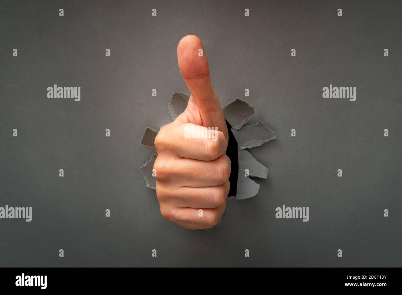 Thumbs up through the hole in a grey paper sheet Stock Photo - Alamy