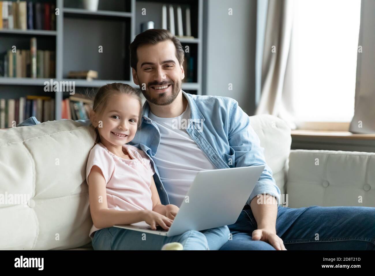 Happy young dad teaching small daughter using computer applications ...