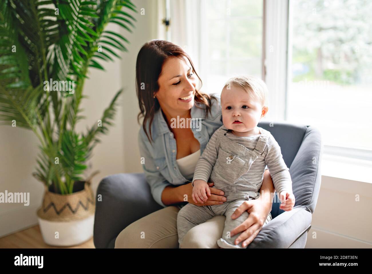 Mother with her baby on a chair at living room Stock Photo - Alamy