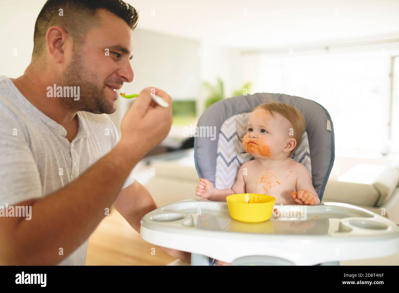A Little baby eating her dinner and making a mess with dad on the side ...