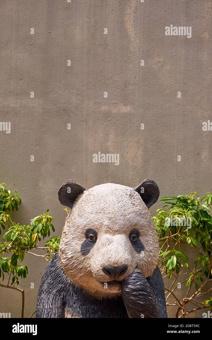 A cute, concrete, painted Giant Panda sculpture, munching. At the Zoo ...