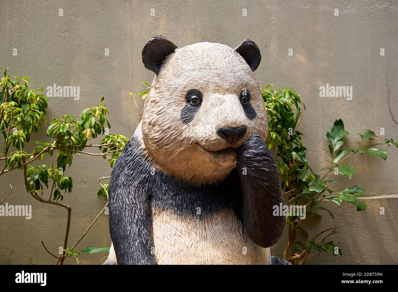 A cute, concrete, painted Giant Panda sculpture, munching. At the Zoo ...
