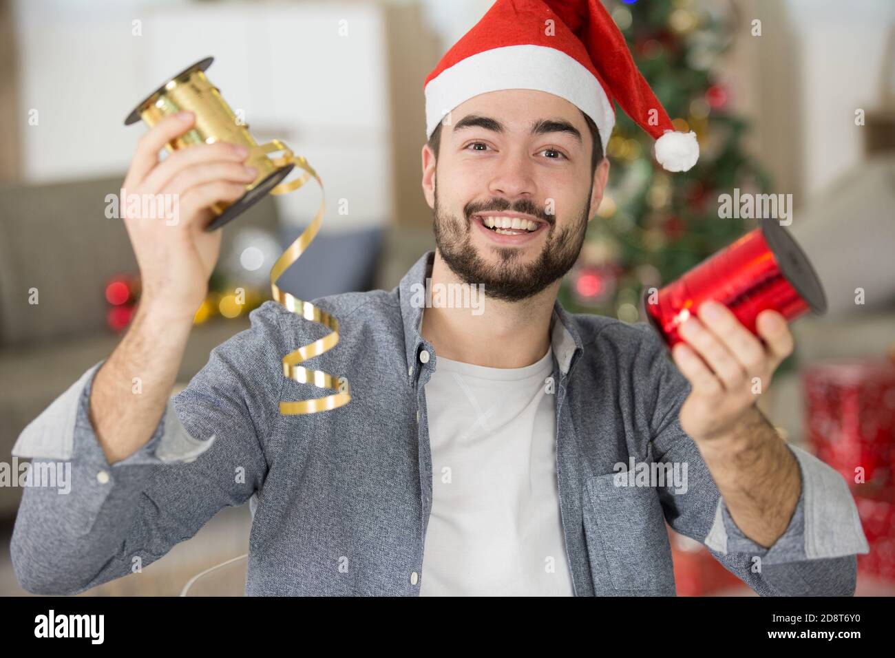 man wearing christmas hat holding reels of ribbon Stock Photo - Alamy