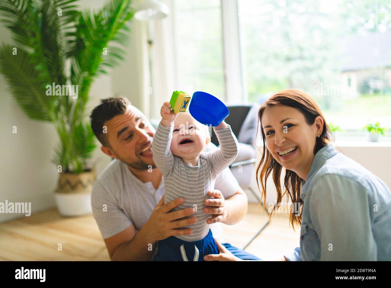 Couple in living room with baby toys Stock Photo - Alamy