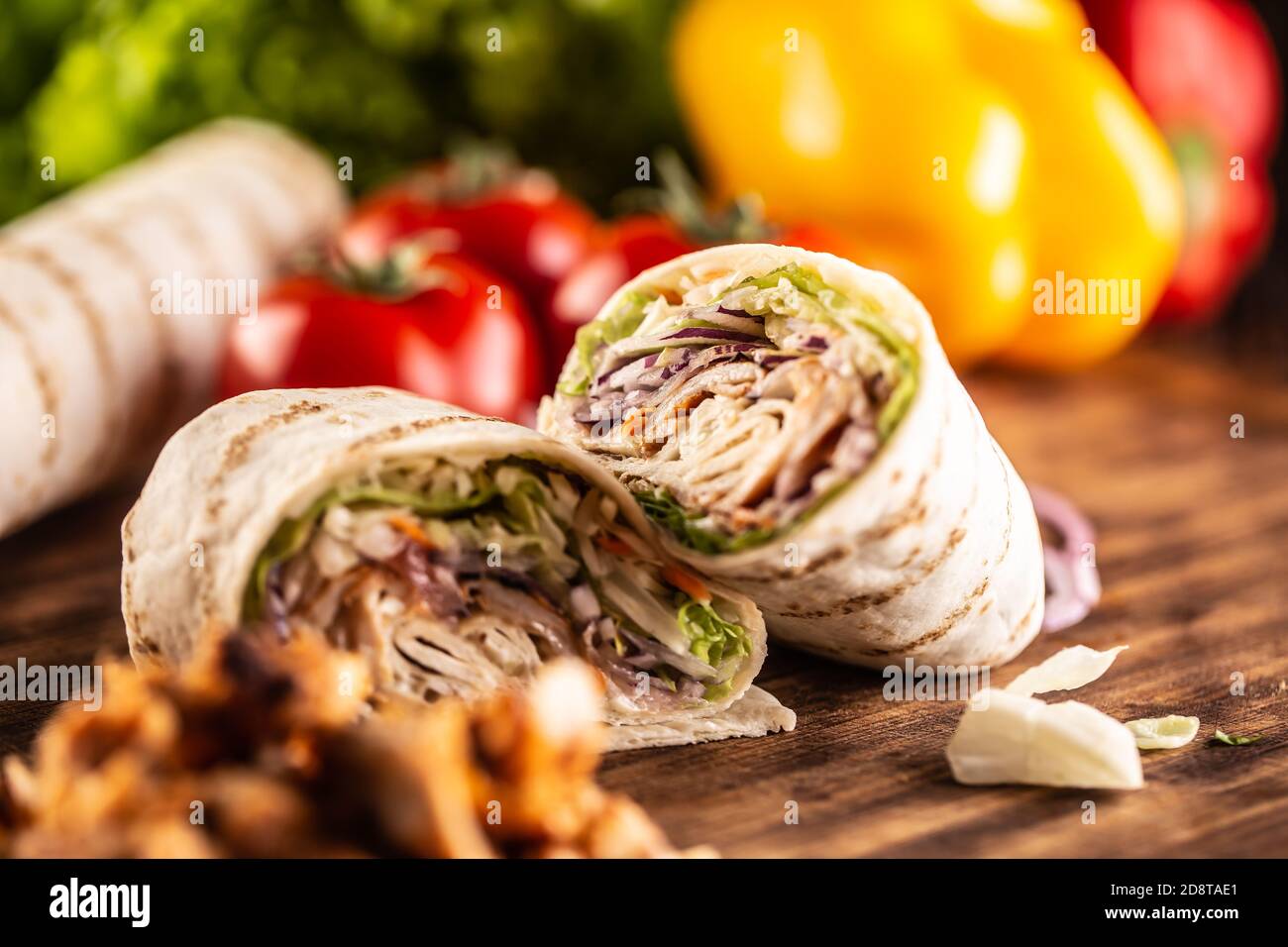 Kebab filled tortilla wraps on a table with vegetables in teh ...