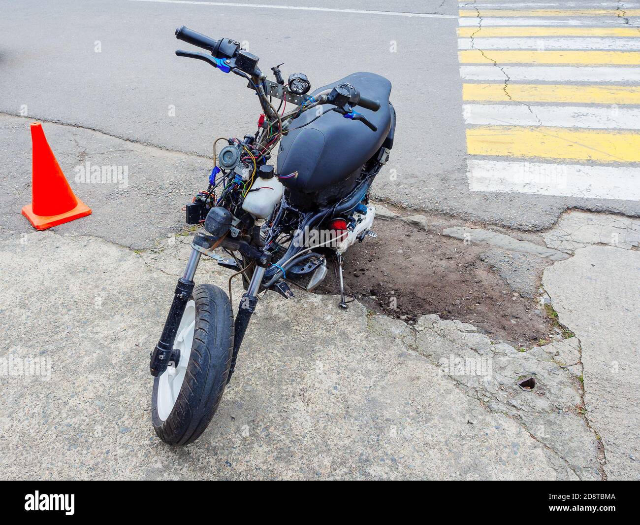 A semi-disassembled moped with wires sticking out is parked on the side ...