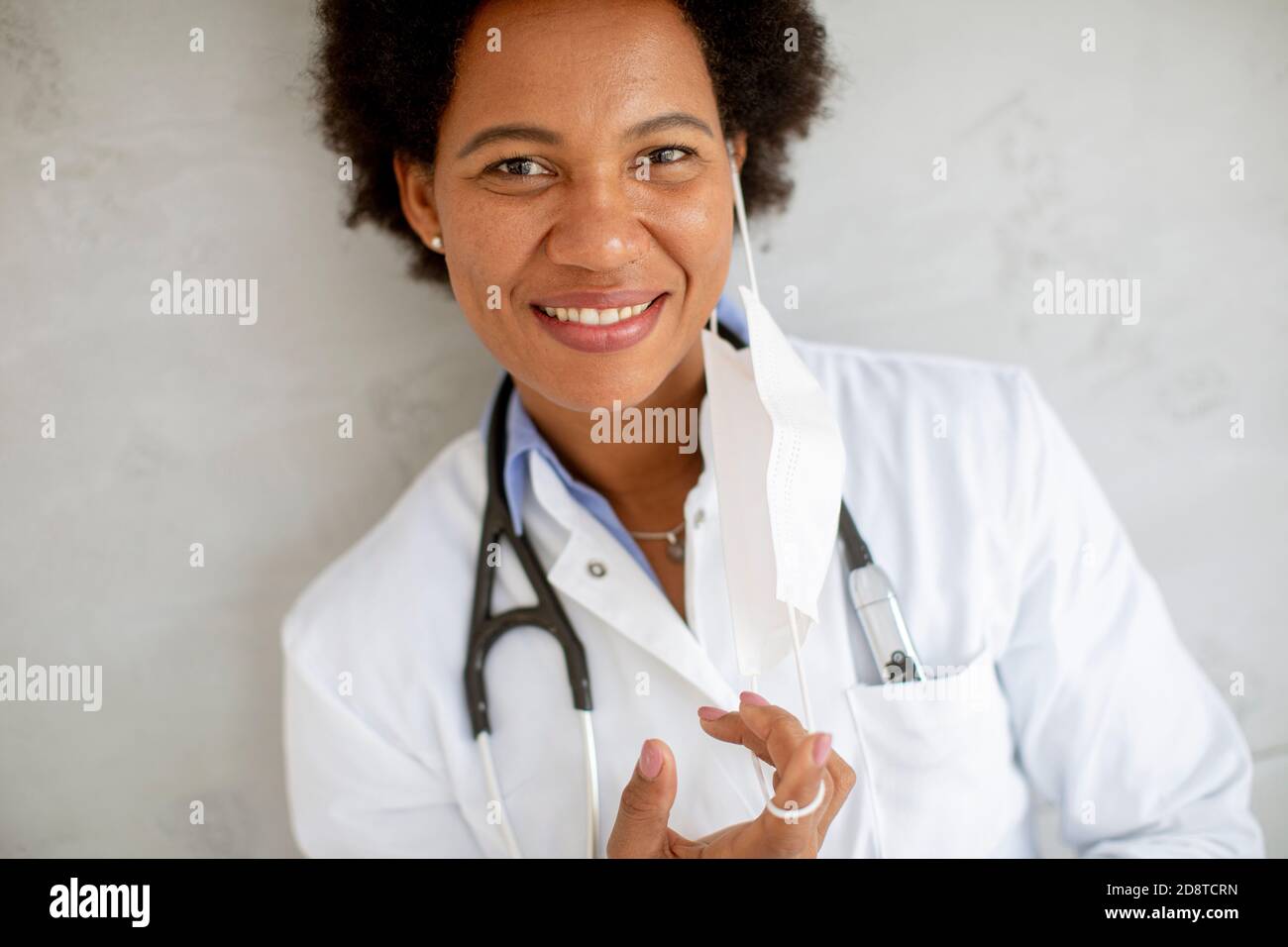Female African American docor wear white uniform and taking off face ...
