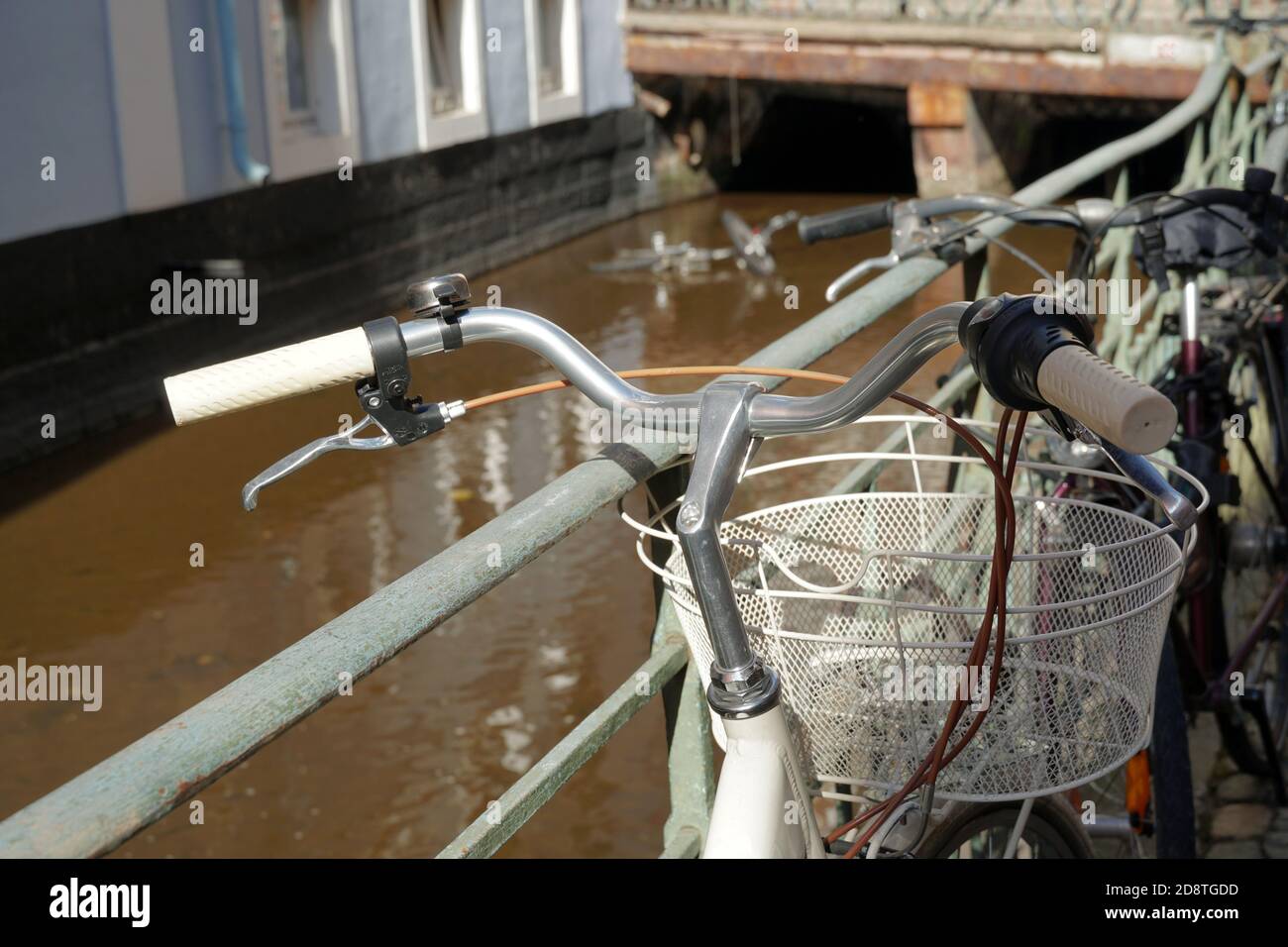 A vintage old bicycle leaned on a metal railing along a city stream in ...