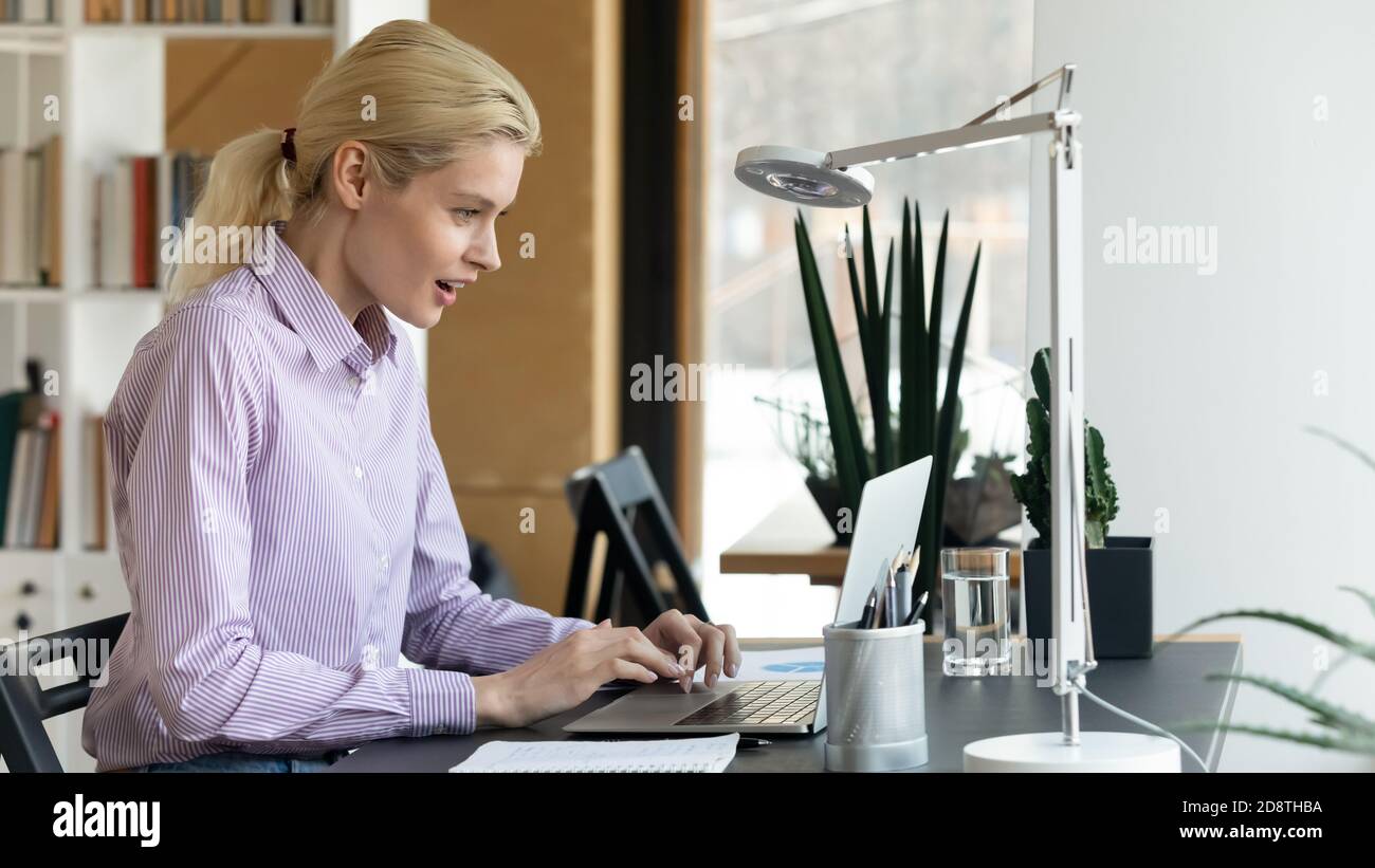Excited young blonde businesswoman looking at computer screen Stock ...