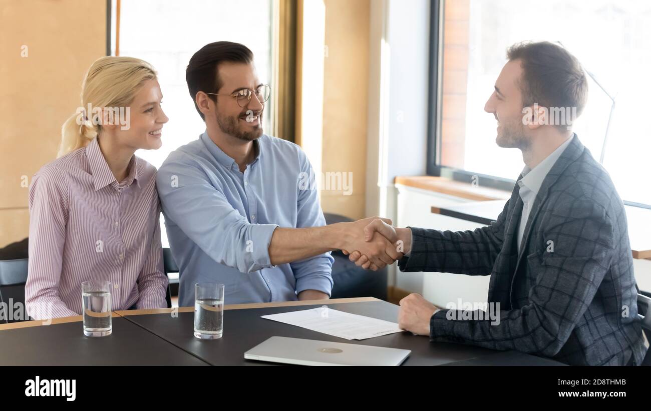 Smiling male financial advisor shaking hands with clients Stock Photo ...