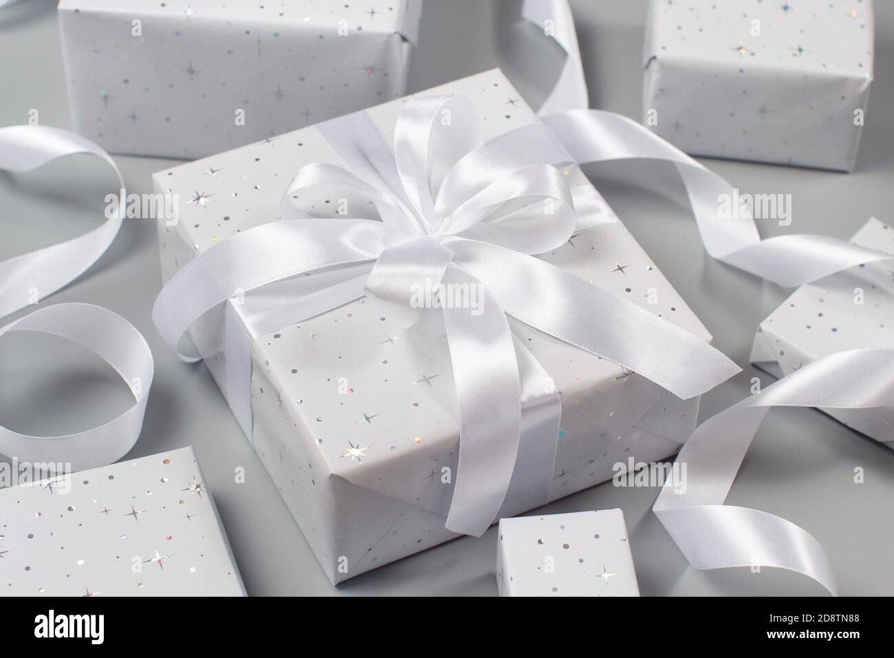 Wrapped grey Gift boxes with white ribbon on grey Stock Photo - Alamy