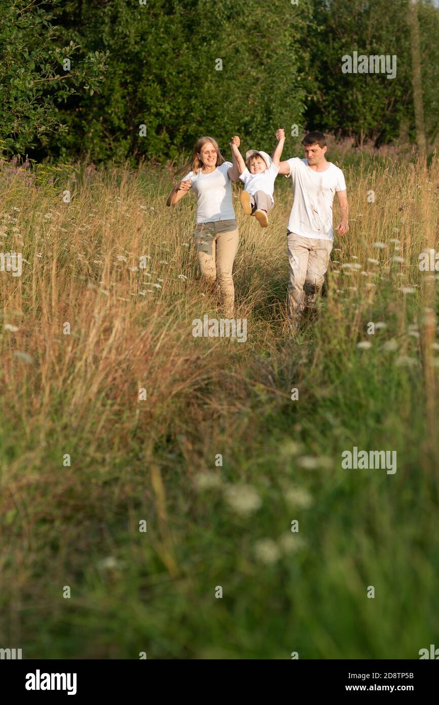 Happy family enjoying walk together at meadow in summer Stock Photo - Alamy