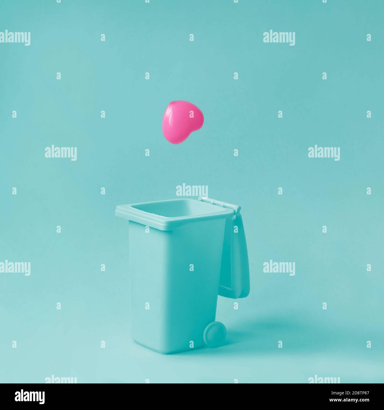 Pink heart falling in garbage bean against pastel blue background ...
