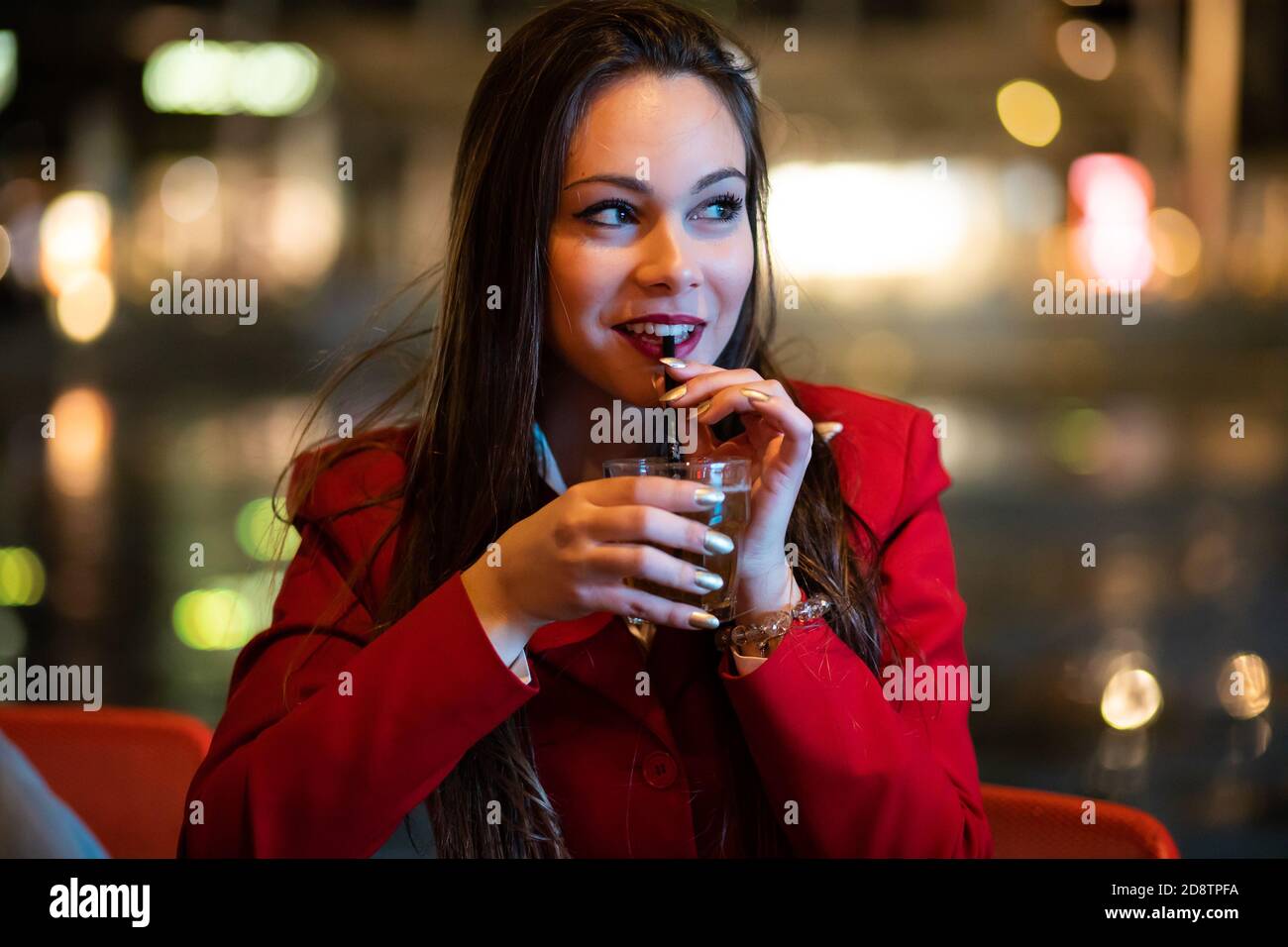 Young woman holding a drink at a night club outdoor Stock Photo - Alamy