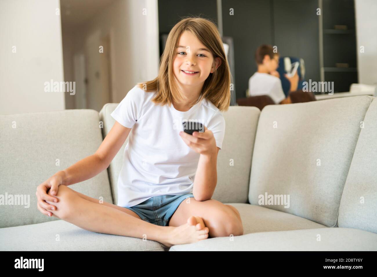 A girl holding remote control and watching TV show Stock Photo - Alamy
