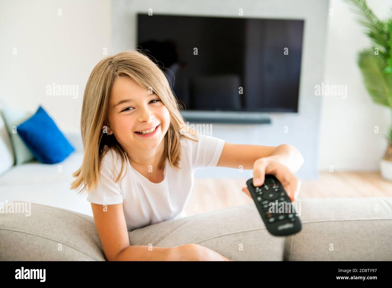A girl holding remote control and watching TV show Stock Photo - Alamy