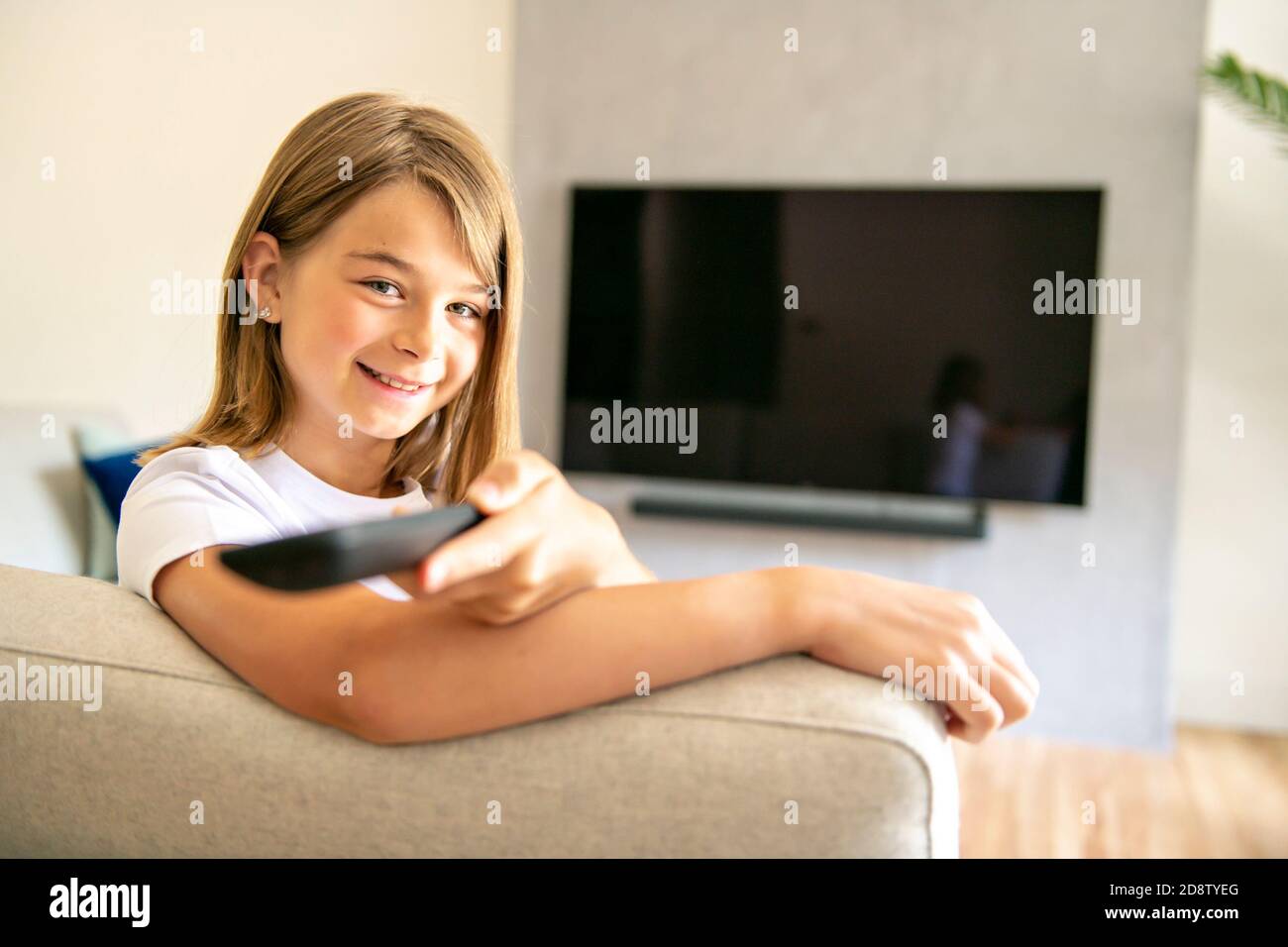 A girl holding remote control and watching TV show Stock Photo - Alamy