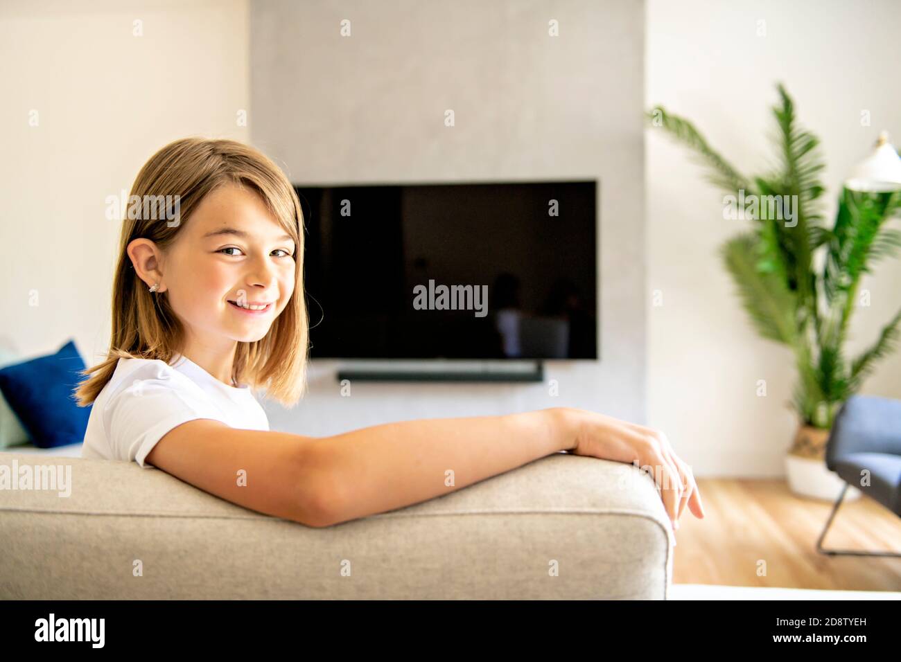 A girl holding remote control and watching TV show Stock Photo - Alamy
