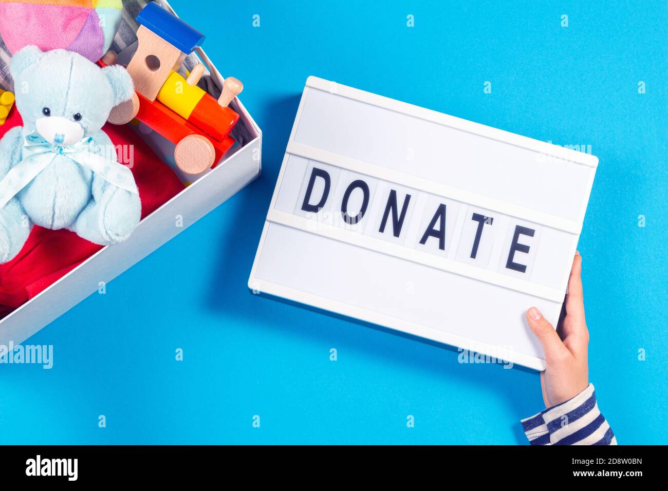 Hands holding lightbox with text donate and donation box with toys ...