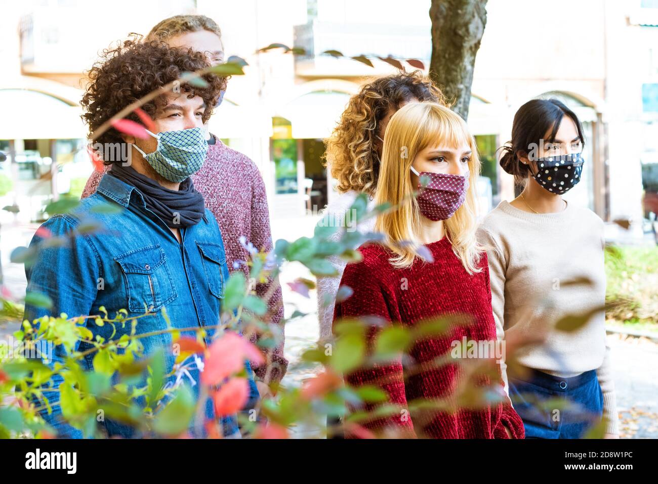 Group of multicultural young people standing outdoor while keeping ...