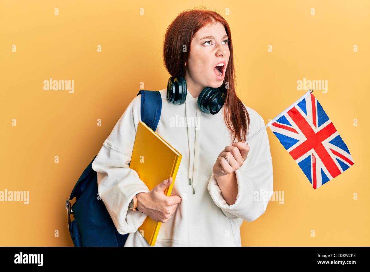 Young red head girl exchange student holding uk flag angry and mad ...