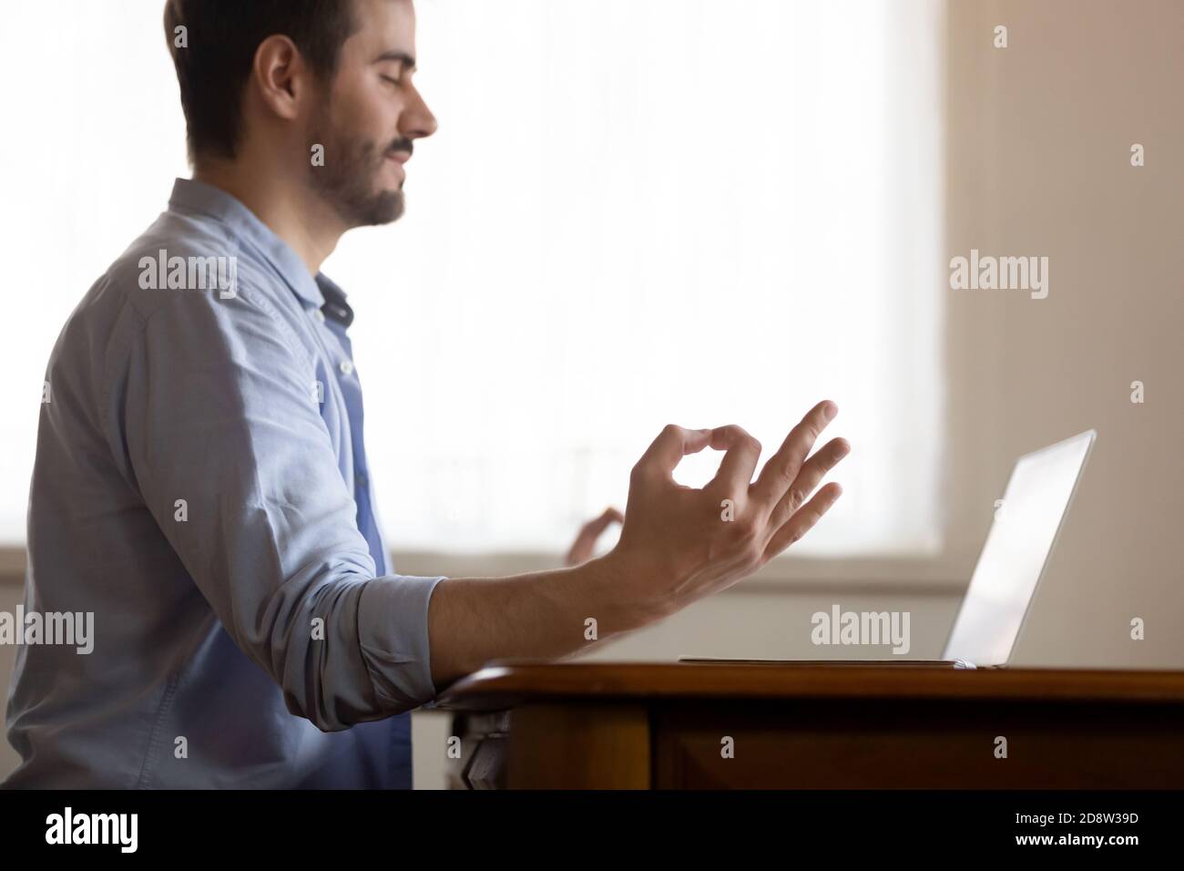 Calm millennial male remote worker relaxing at workplace practicing ...