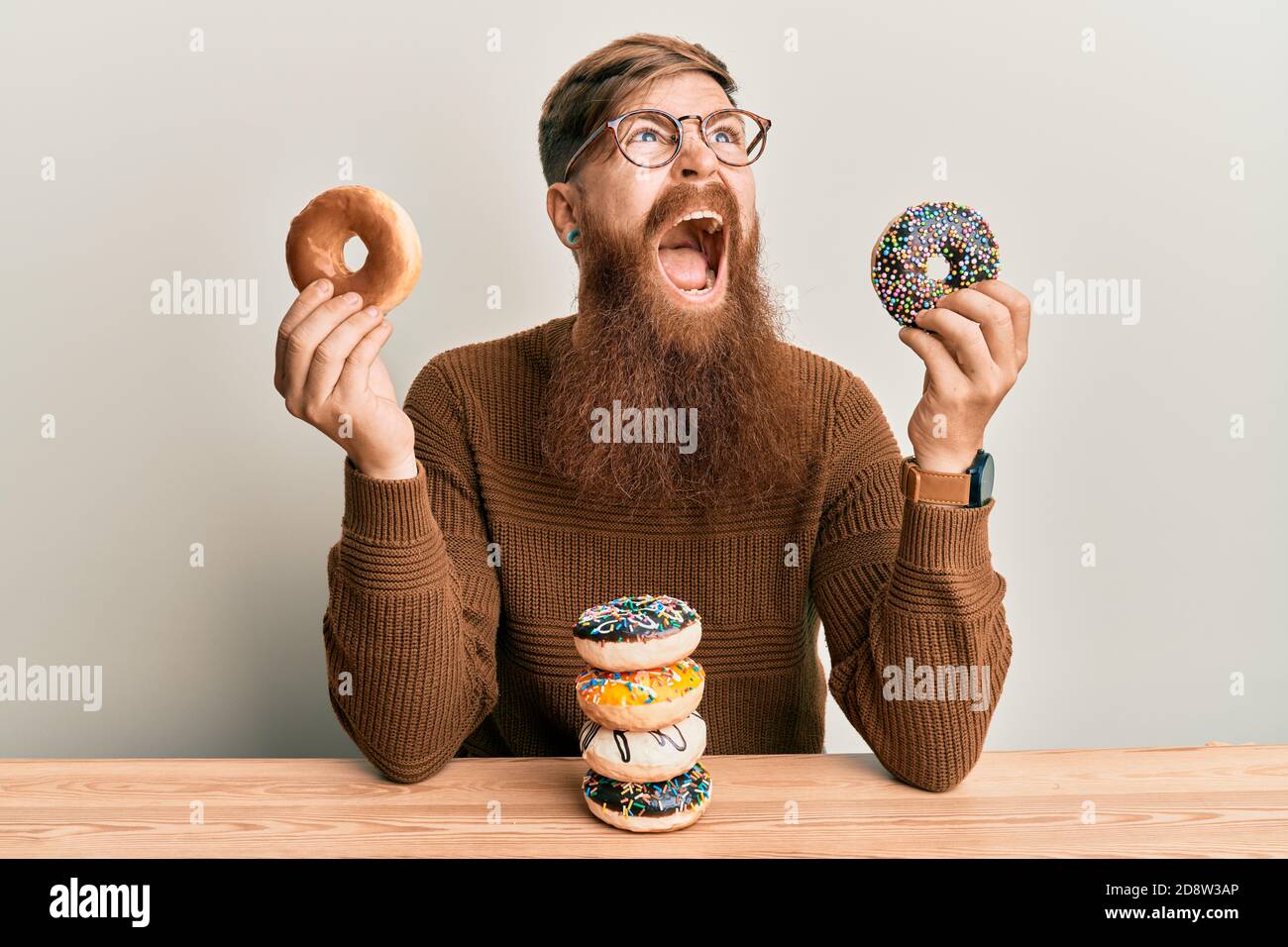 Young irish redhead man eating doughnut for breakfast angry and mad ...