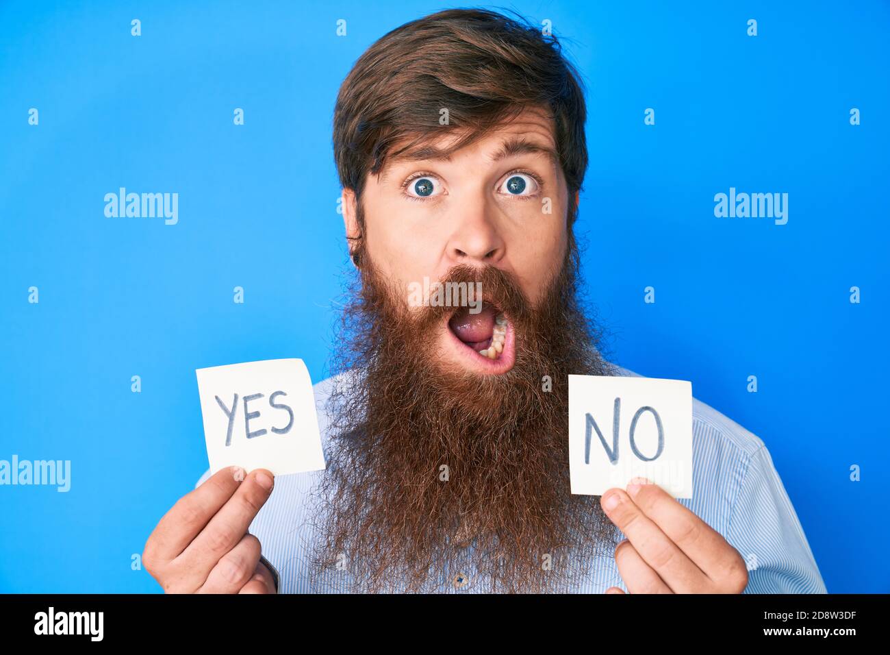 Handsome young red head man with long beard holding yes and no reminder ...