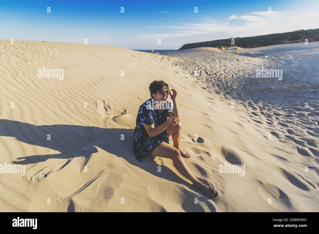 Young smiling female sitting on white sand Stock Photo - Alamy