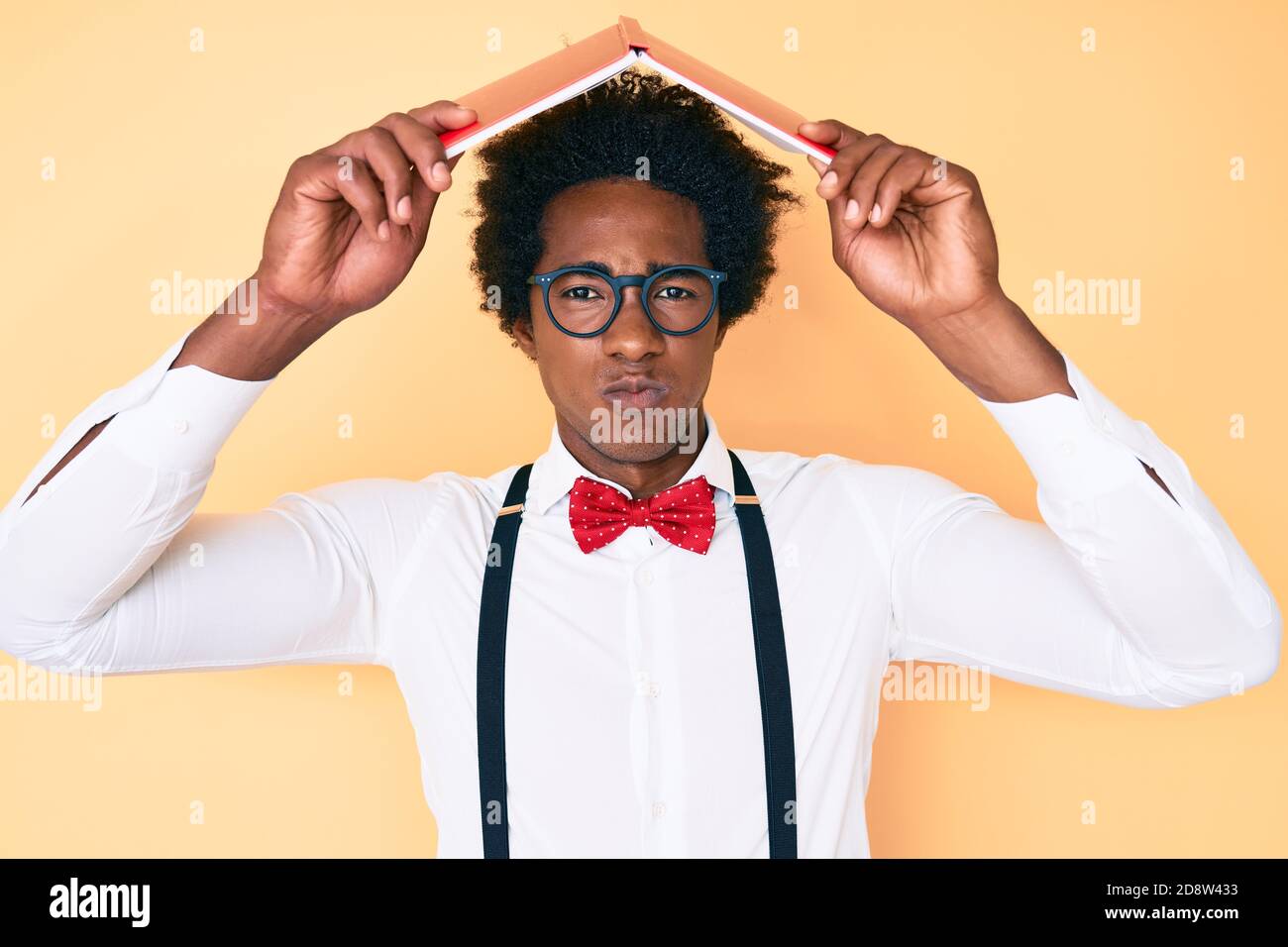 Handsome african american nerd man with afro hair holding book over ...