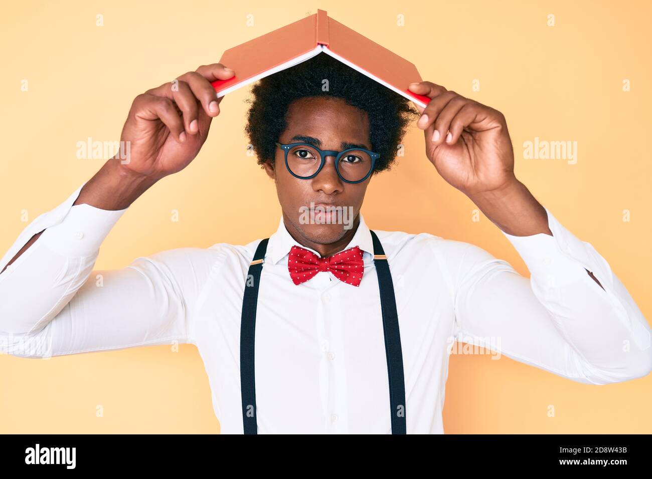 Handsome african american nerd man with afro hair holding book over ...