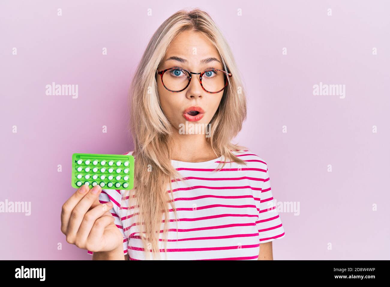 Beautiful caucasian blonde girl holding birth control pills scared and ...