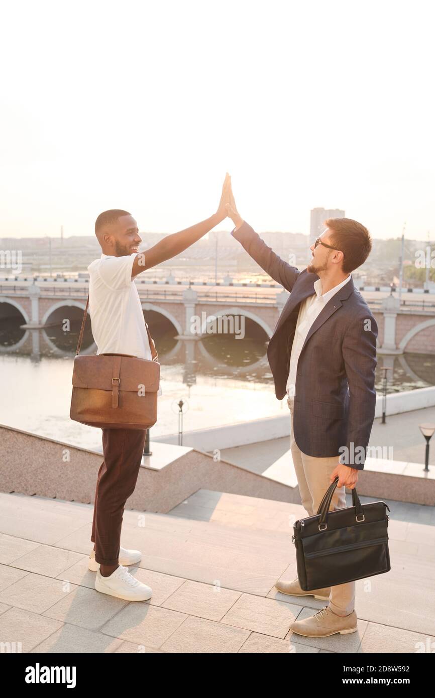 Two young business partners of various ethnicities giving one another ...