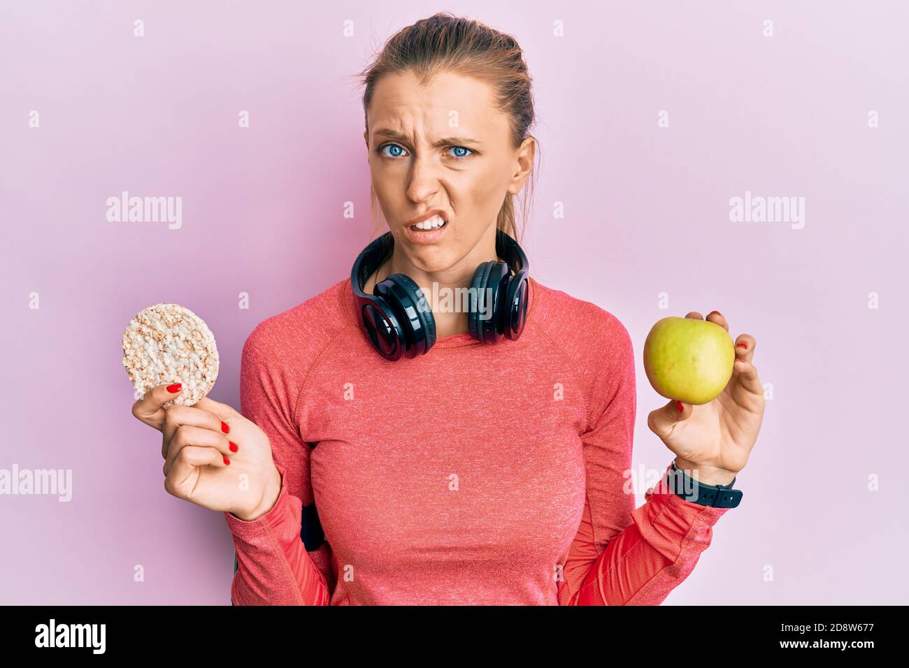 Beautiful caucasian sports woman holding green apple and rice crackers ...